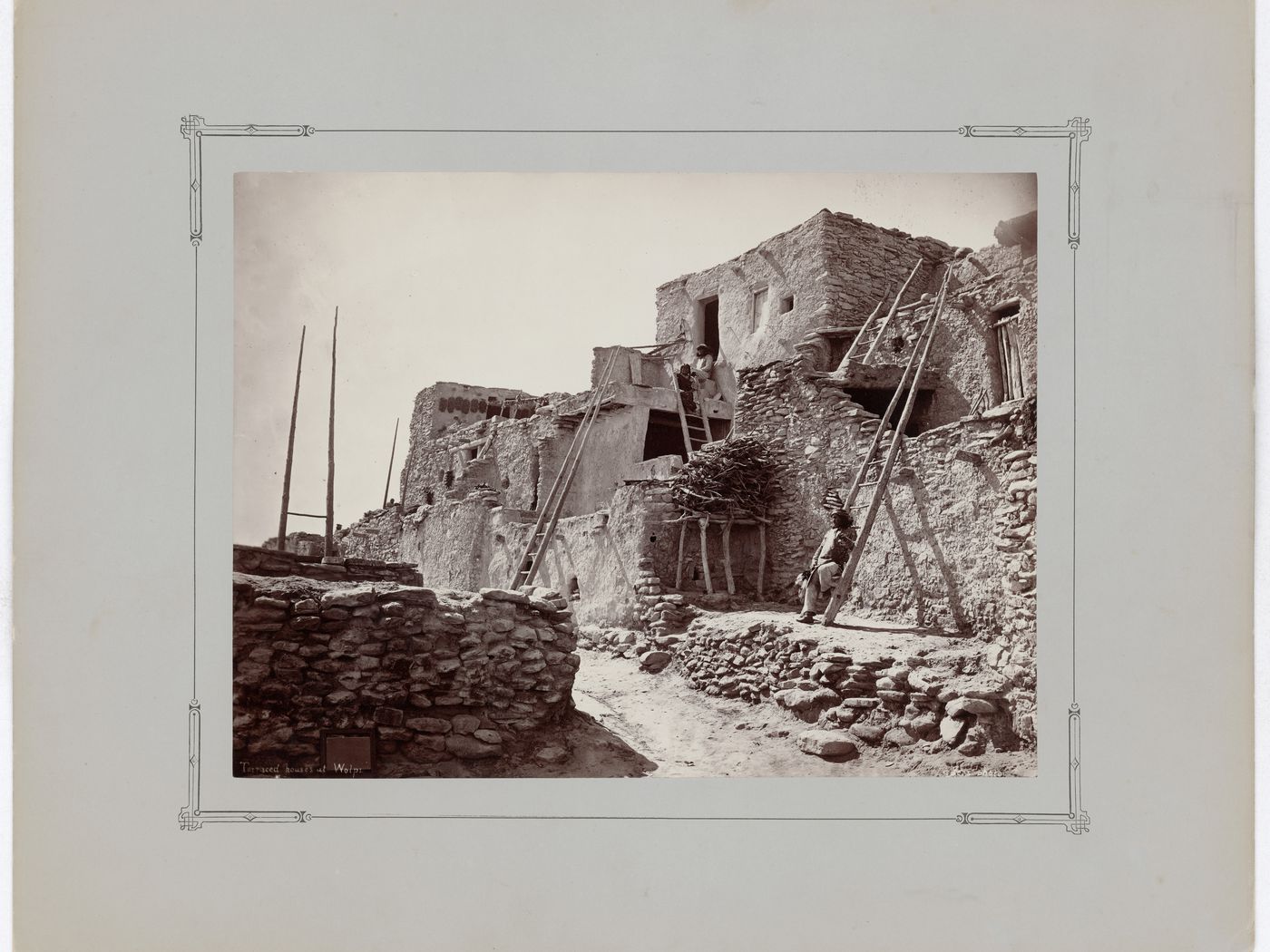 View of Walpi on the First Mesa showing terraced houses and three seated people, Hopi ...
